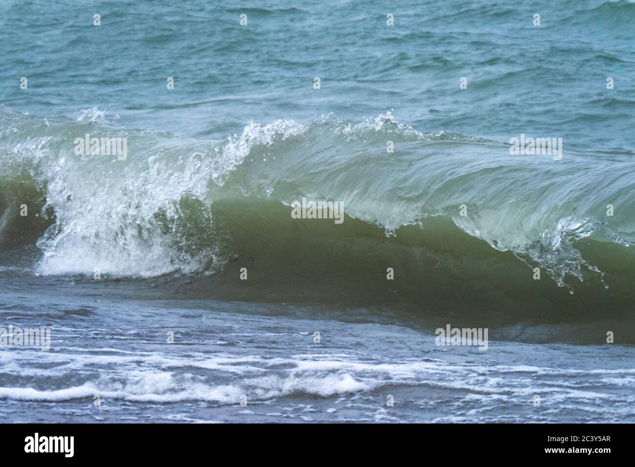 a large wave breaking on a shore with the underside of the curl visible ...