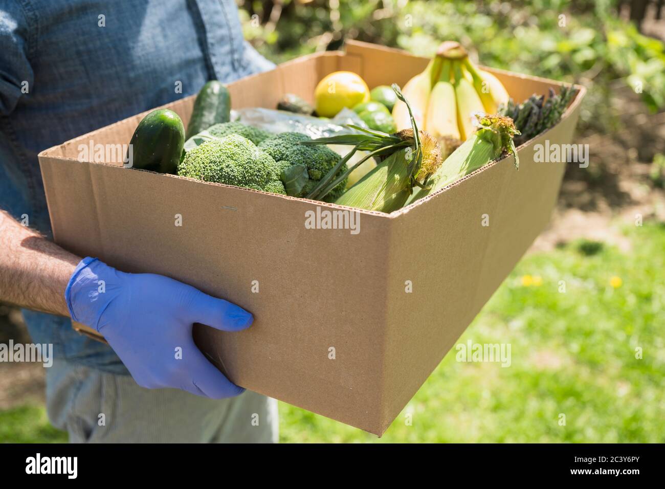 Delivery person holding box with fruit and vegetables Stock Photo - Alamy