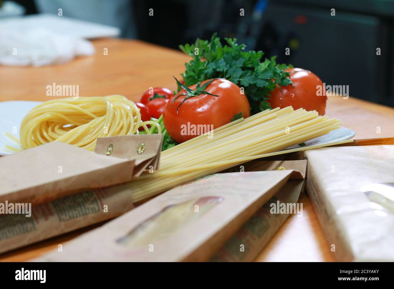 Uncooked pasta noodles inside a paper packaging with fresh tomatoes and ...