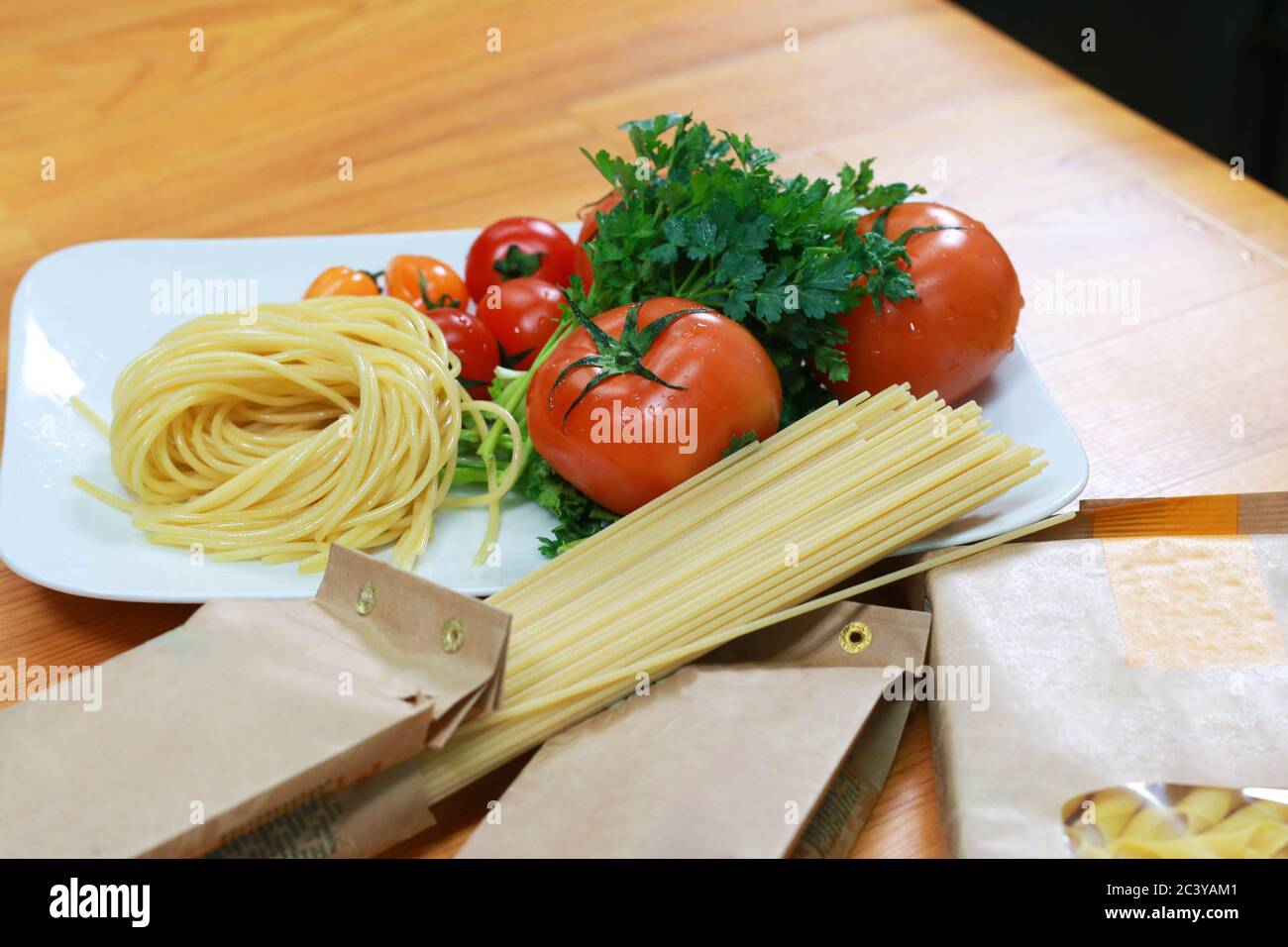 Uncooked pasta noodles inside a paper packaging with fresh tomatoes and ...