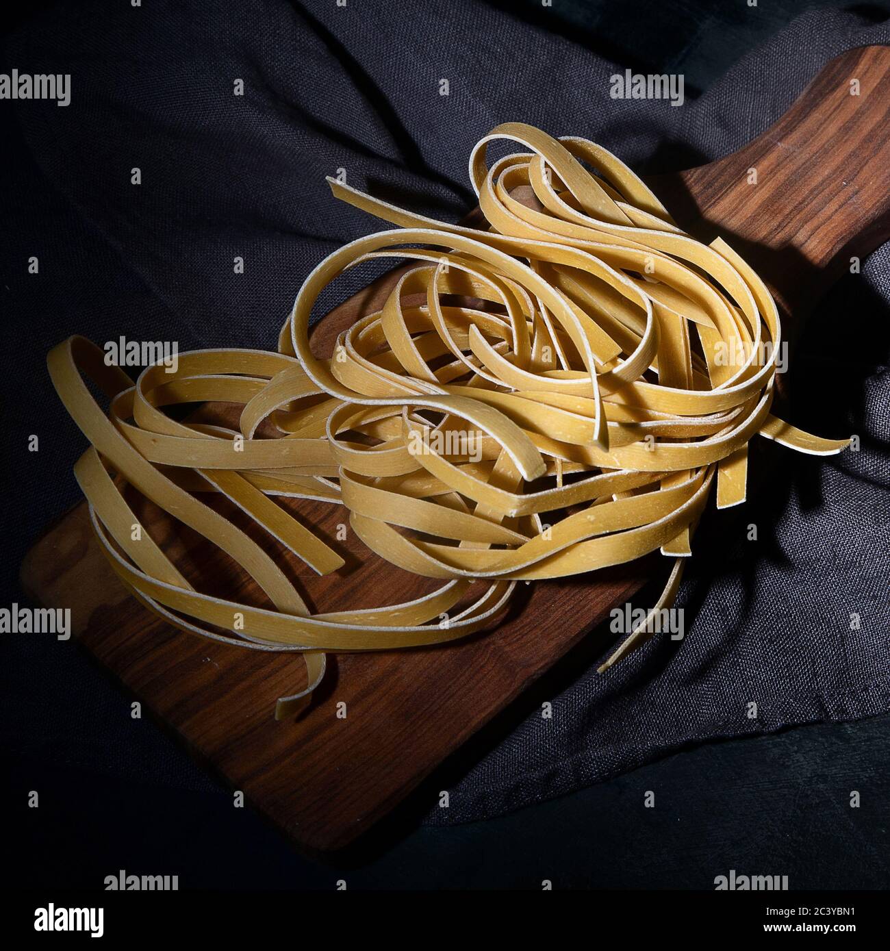 Italian raw uncooked tagliatelle pasta on black background Stock Photo ...