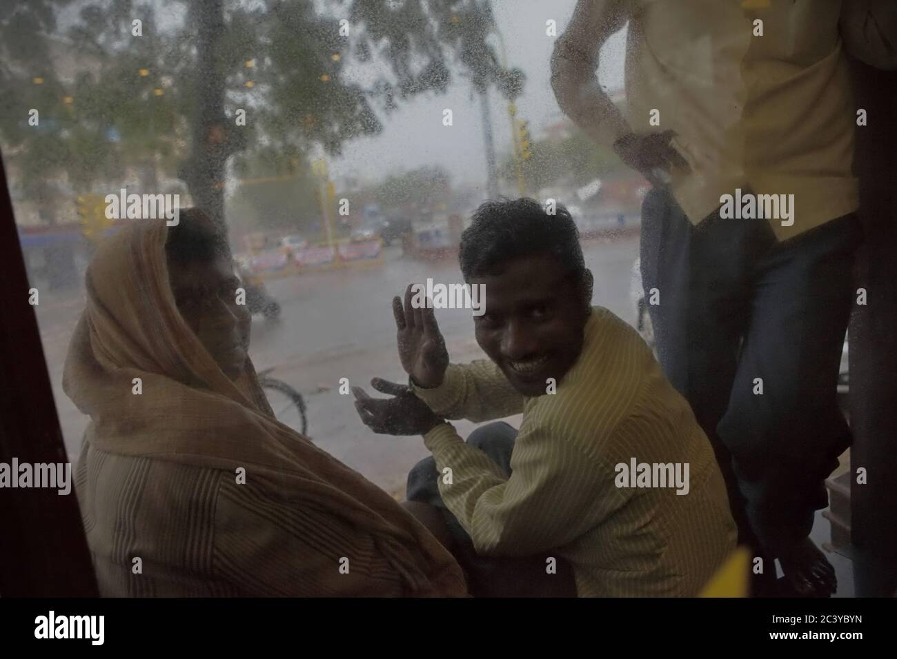 Men cheering through a glass window as they get shelter from rain in a ...