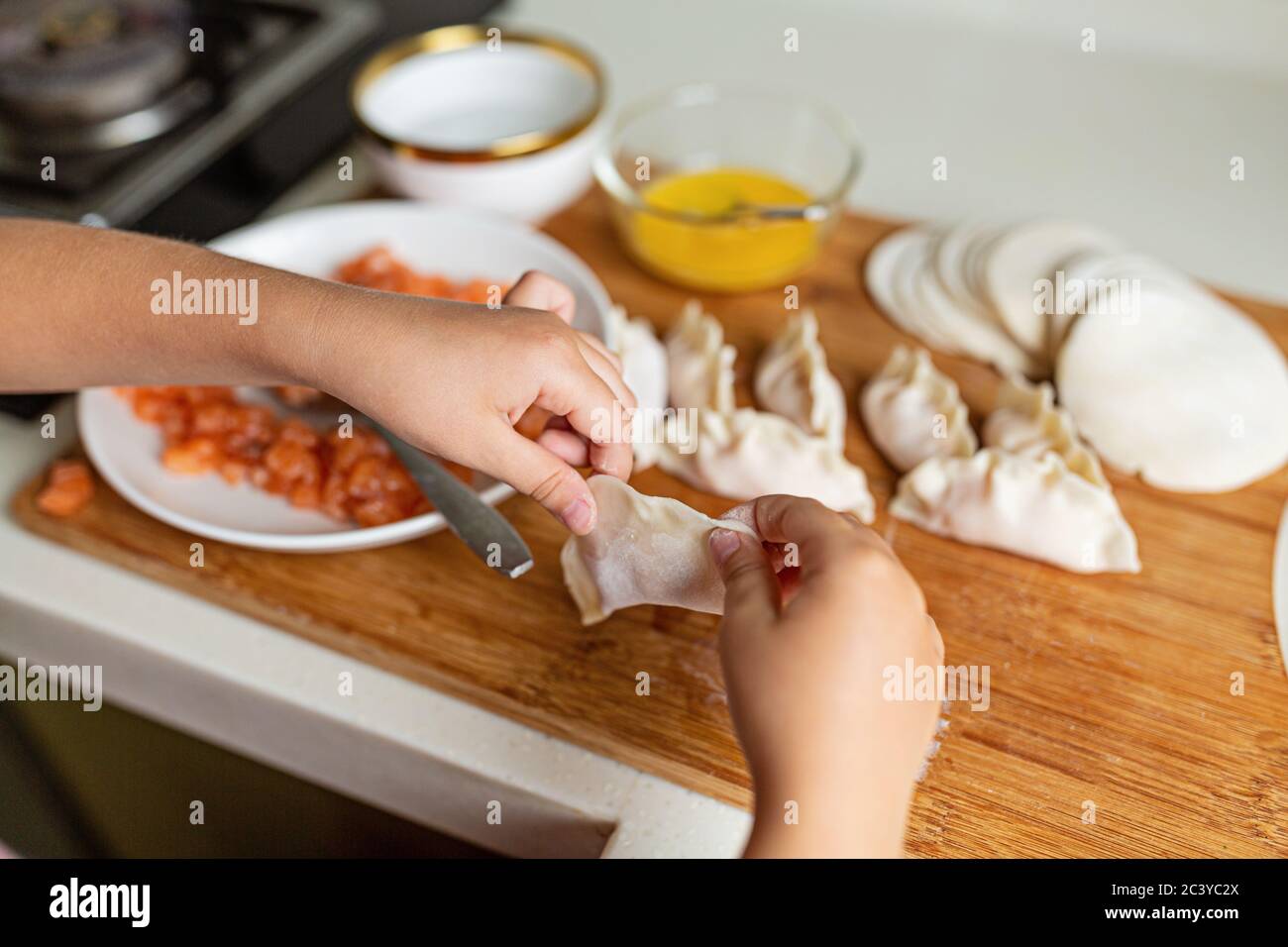Kid hands cooking dumplings with raw salmon on the kitchen. Stay at ...