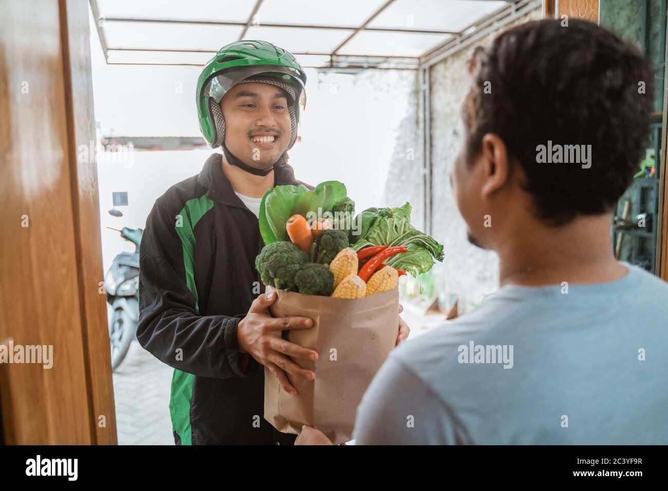asian male courier delivering grocery to customer. food online delivery ...