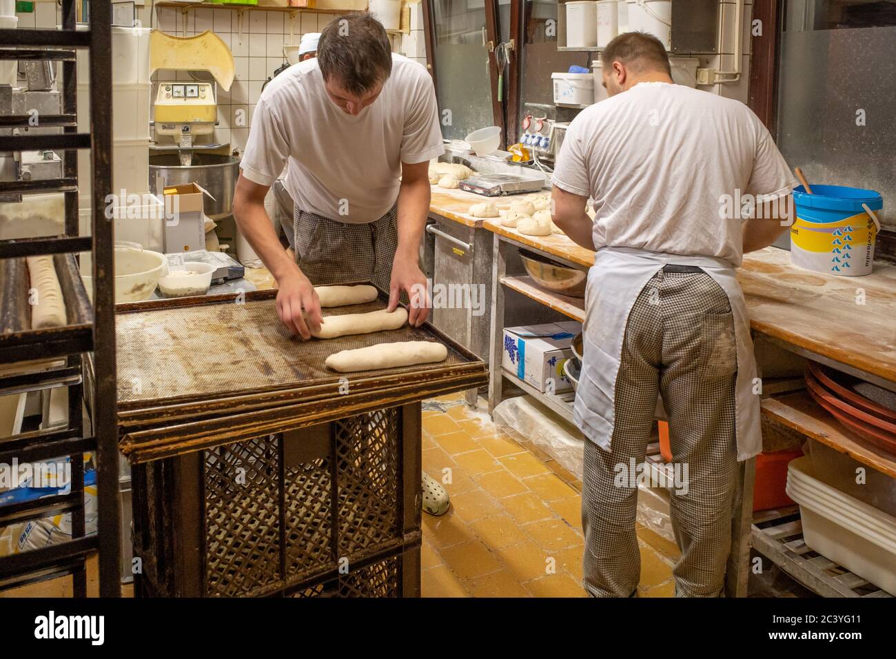 in a bakery two bakers put loaves of bread on a baking tray Stock Photo ...