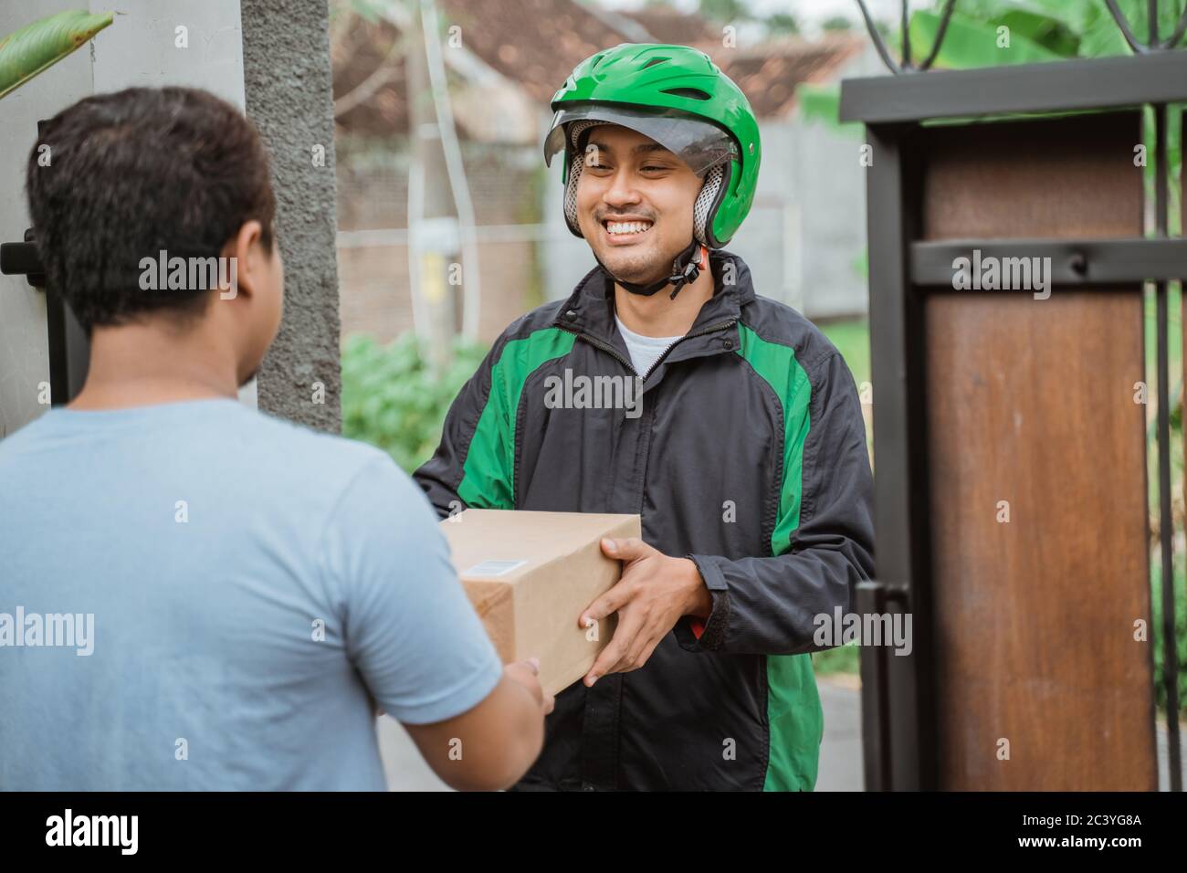 male courier with helmet delivering package to customer at home Stock ...