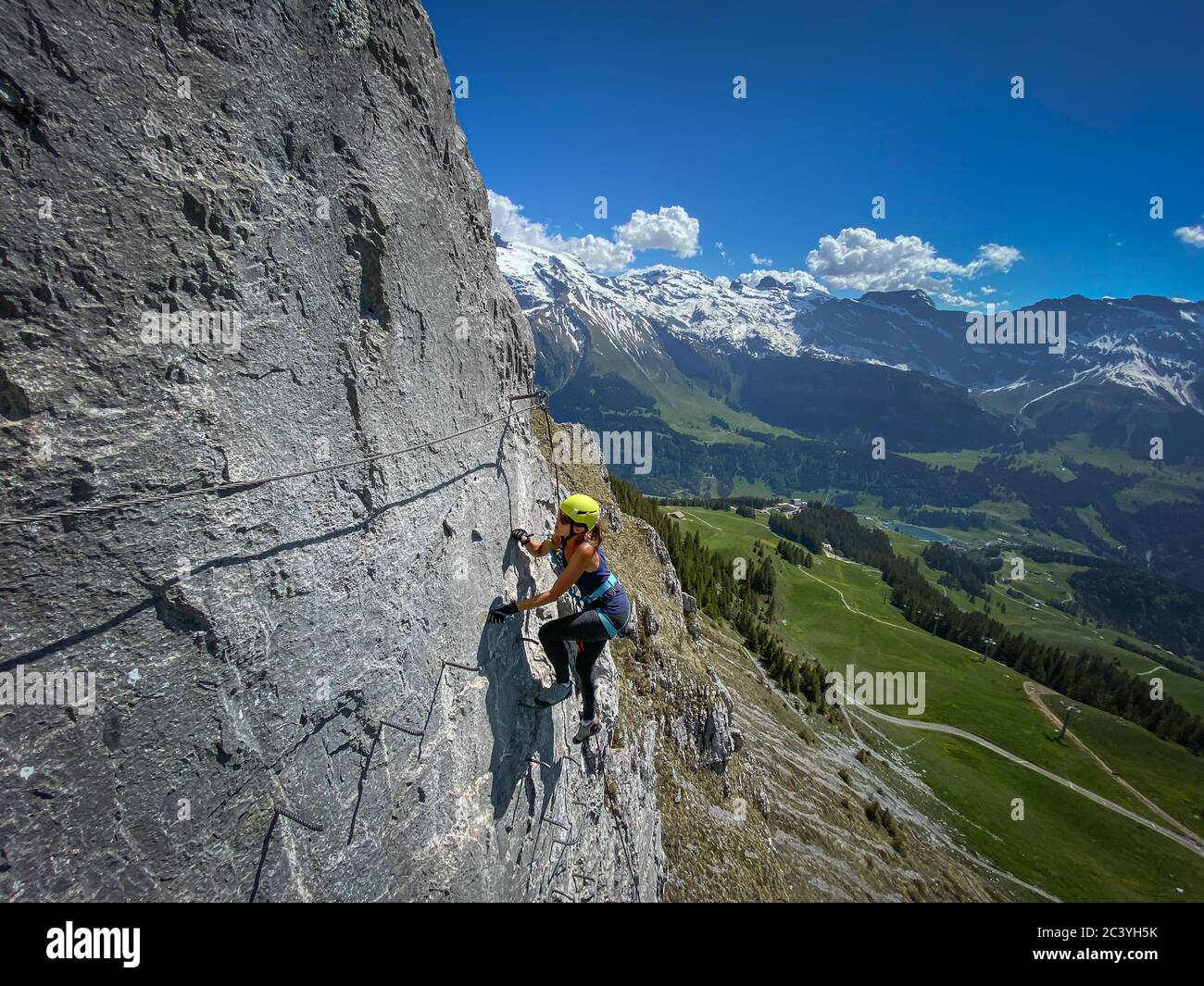 Pretty female climber on a steep Via Ferrata in the Swiss Alps ...