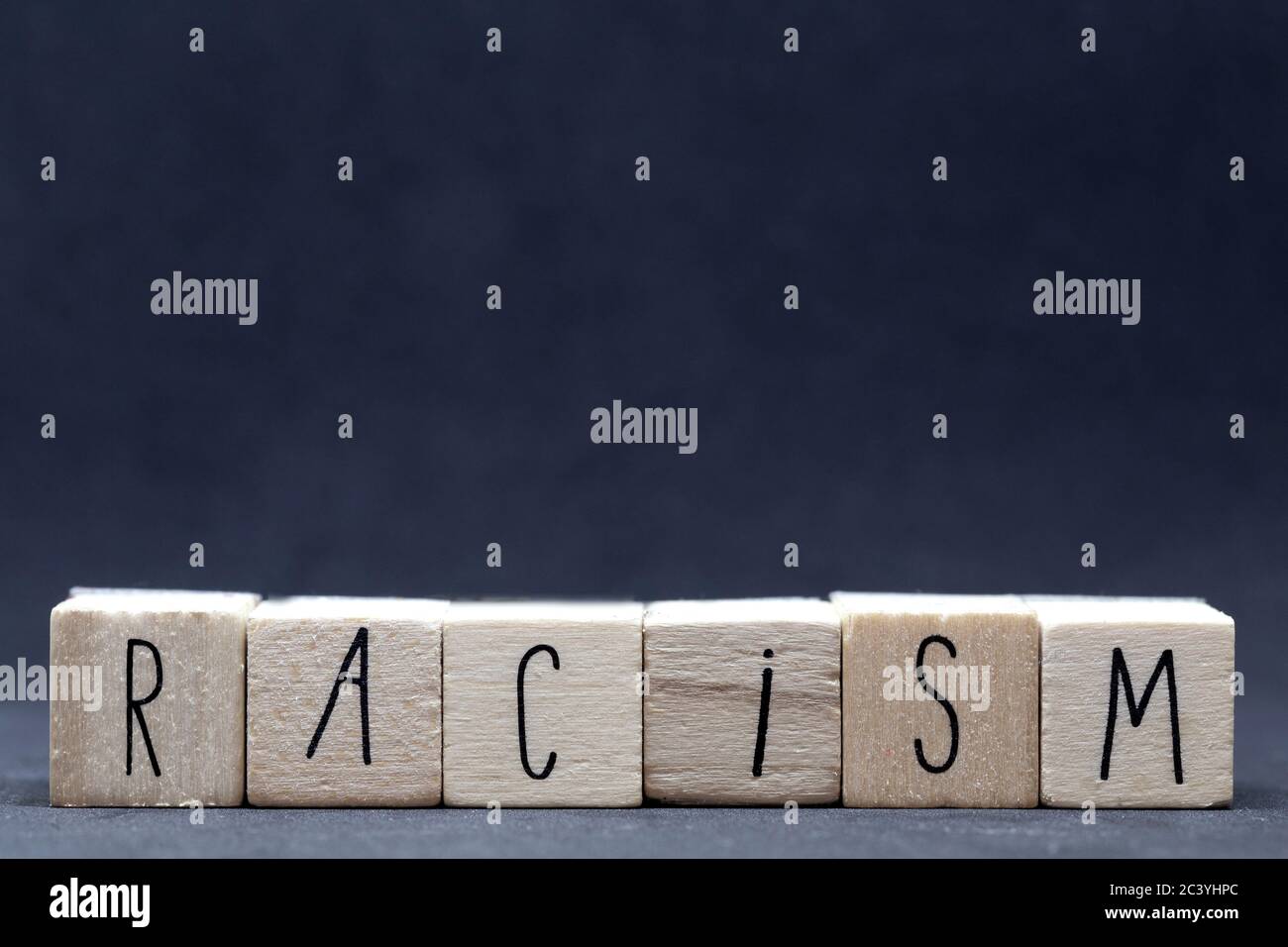 Wooden cubes with the word racism on dark background, black lives ...