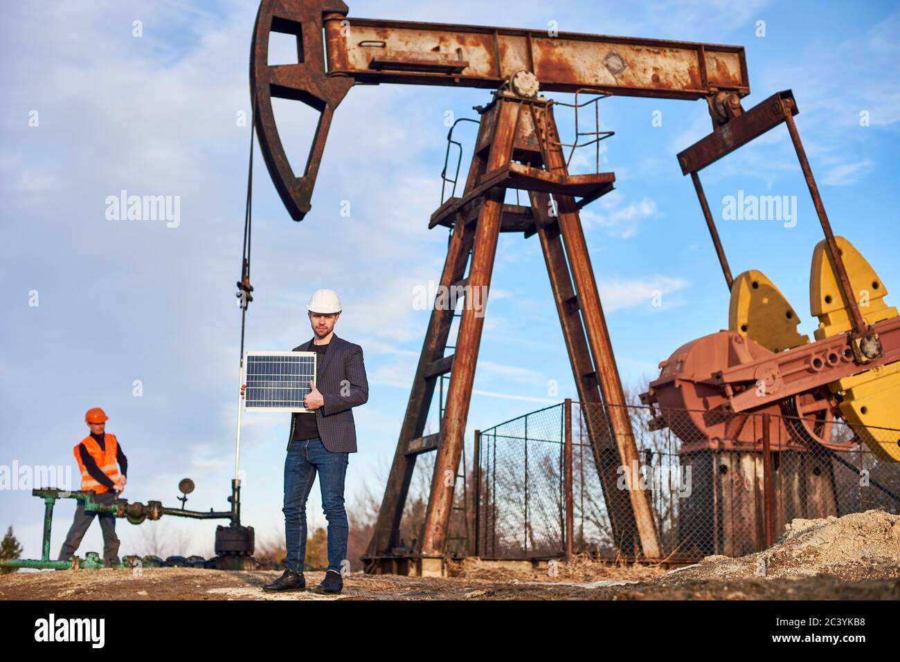 Portrait of smiling businessman in suit jacket, white helmet, holding ...