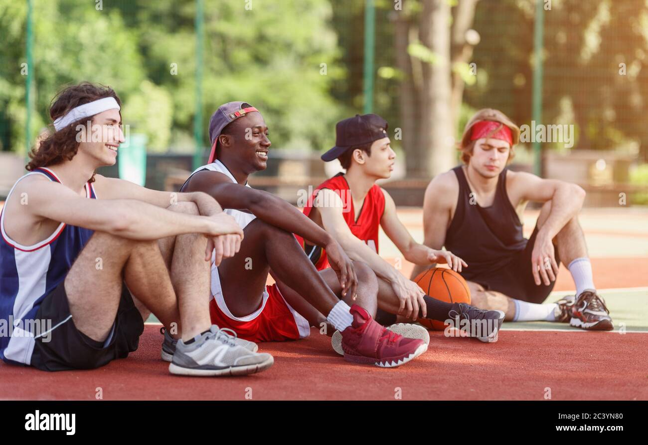 Diverse team of professional basketball players talking during their ...