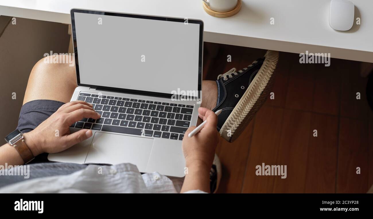 Overhead shot of male entrepreneur working with mock-up laptop on is ...