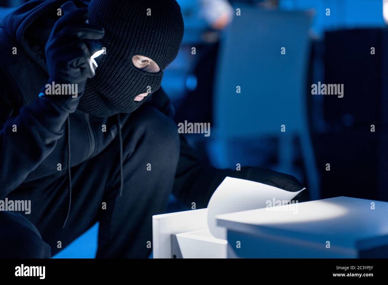 Masked thief holding and reading confidential documents Stock Photo - Alamy