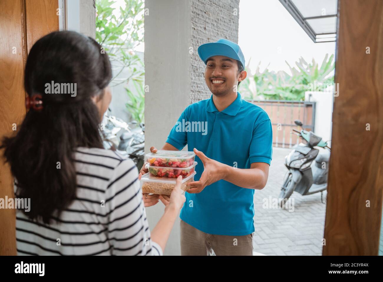 Delivery man delivering food to a woman at home. online food shopping ...