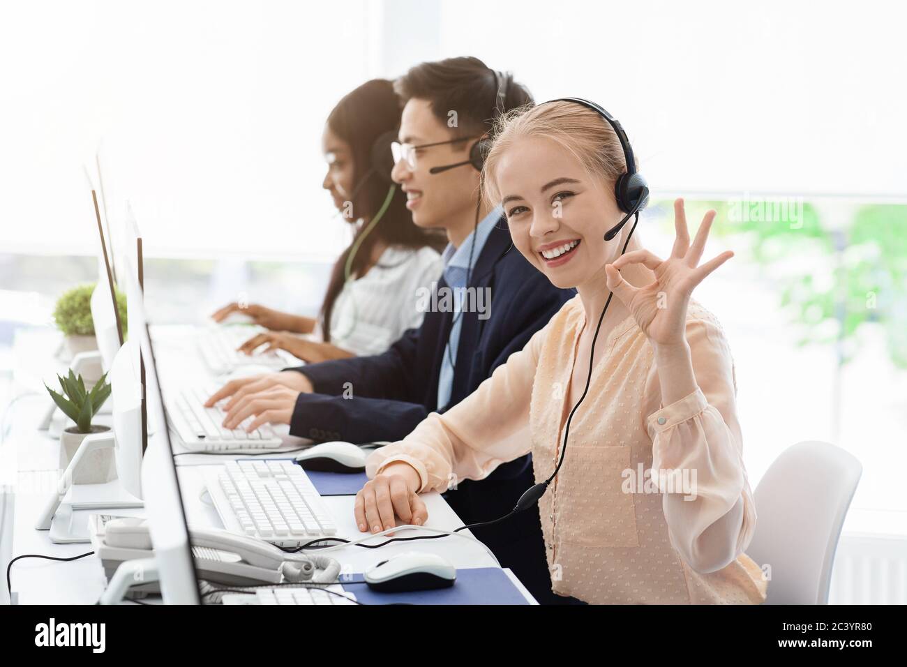 Customer service executive showing okay gesture and her colleagues ...
