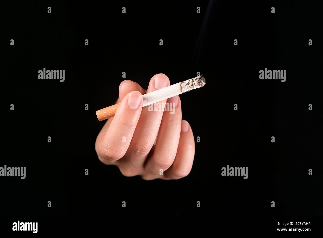 hand with smoking cigarette emerges from darkness, inviting the viewer ...
