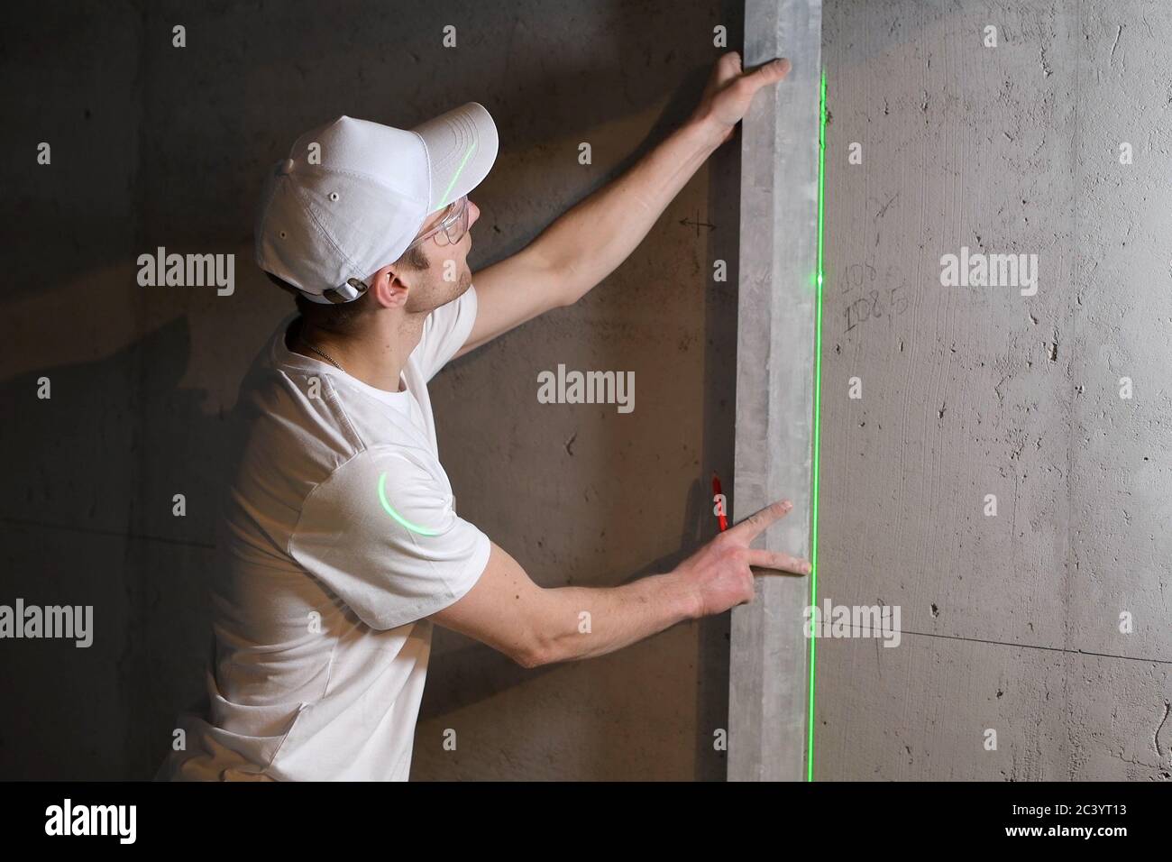 master applies the rule to the wall, checking laser level, applies the ...