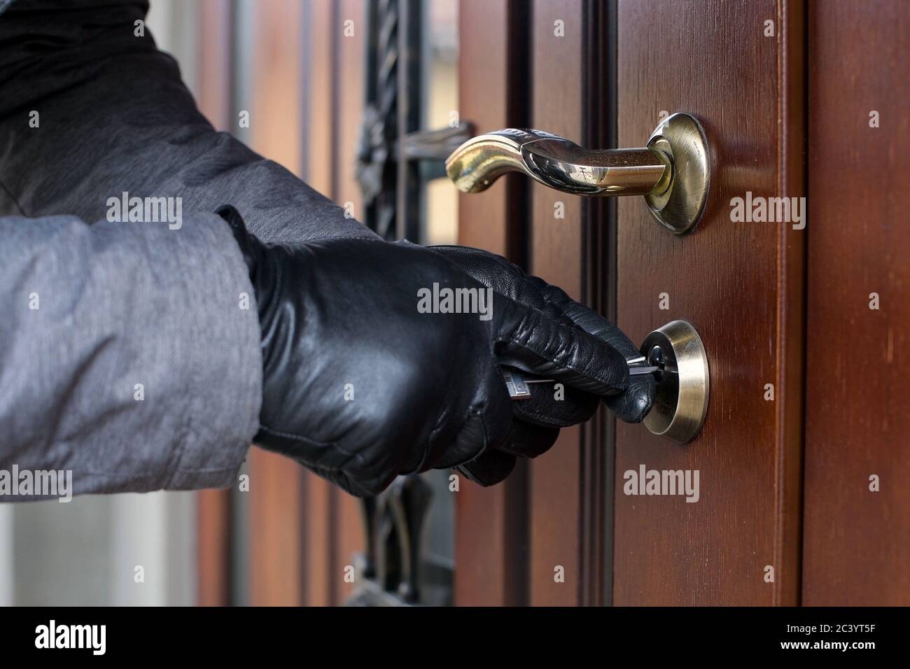a thief in gloves opens the door lock of a private house and penetrates ...