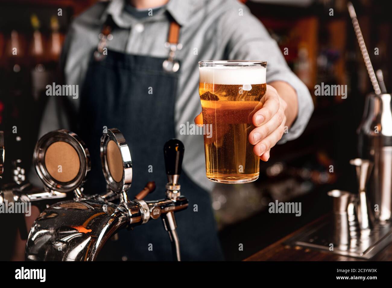 Bartender serves light beer to client at bar interior of pub Stock ...