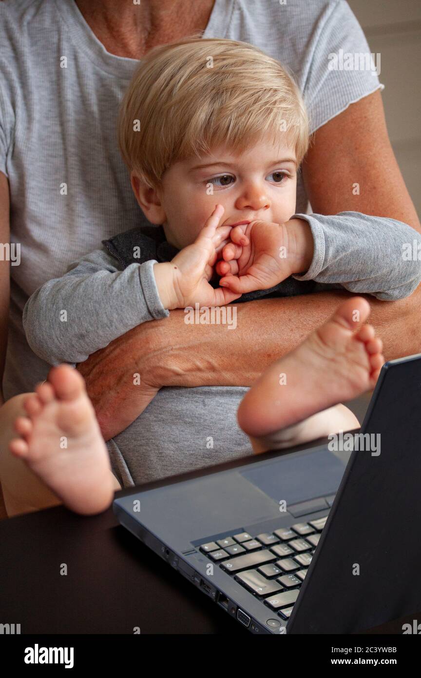 Little child looking excited at something on a laptop computer monitor ...