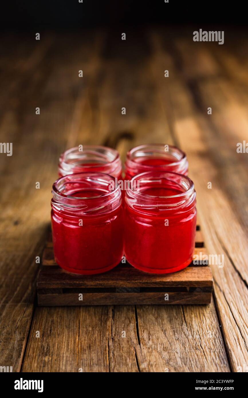 Red colored alcoholic shooters, or shot drinks on wooden table, with ...