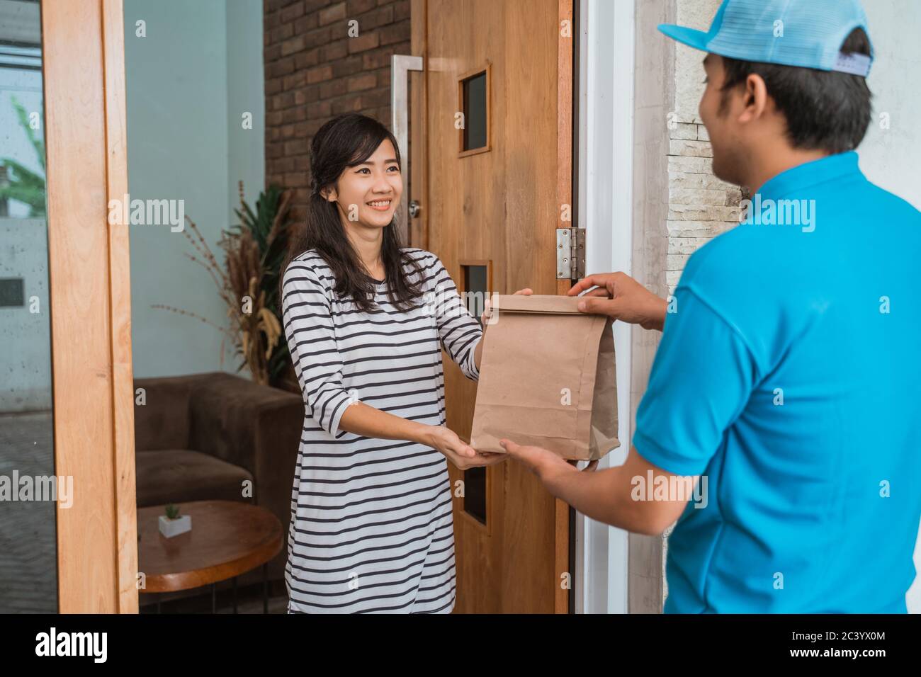 Delivery man delivering food to a woman at home. online food shopping ...