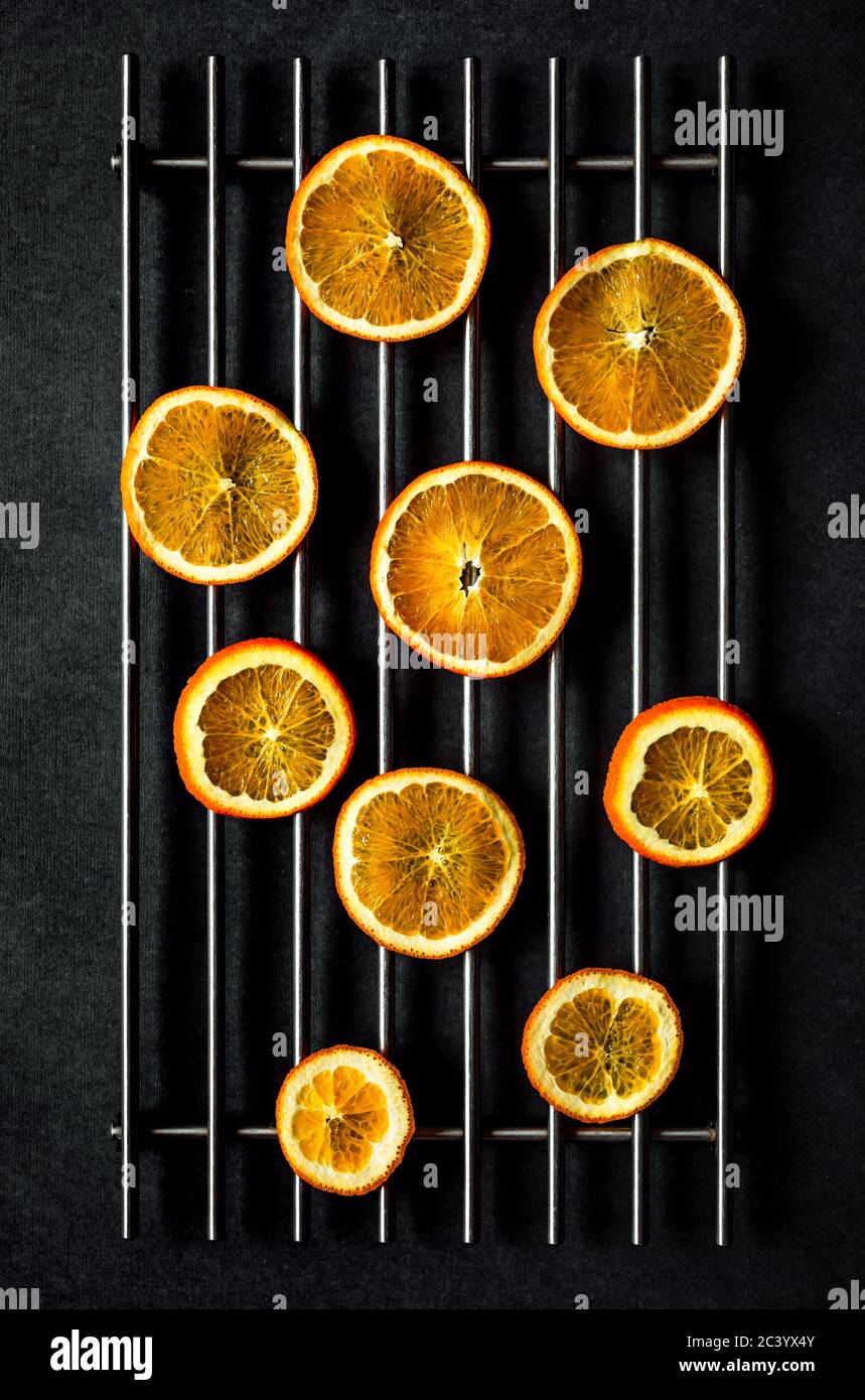 Top view of a sliced orange on a steel grate, deep grey background ...
