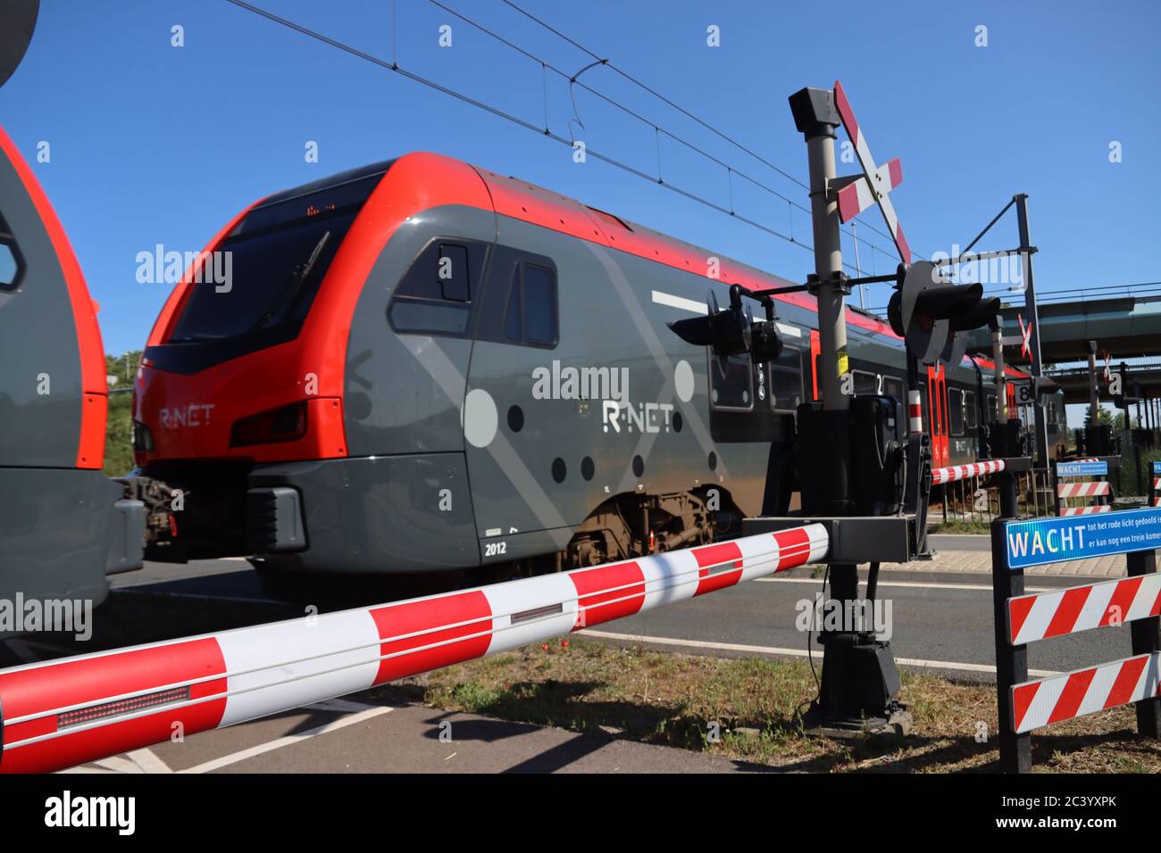 Red and black R-net train at a railroad crossing in Waddinxveen between ...
