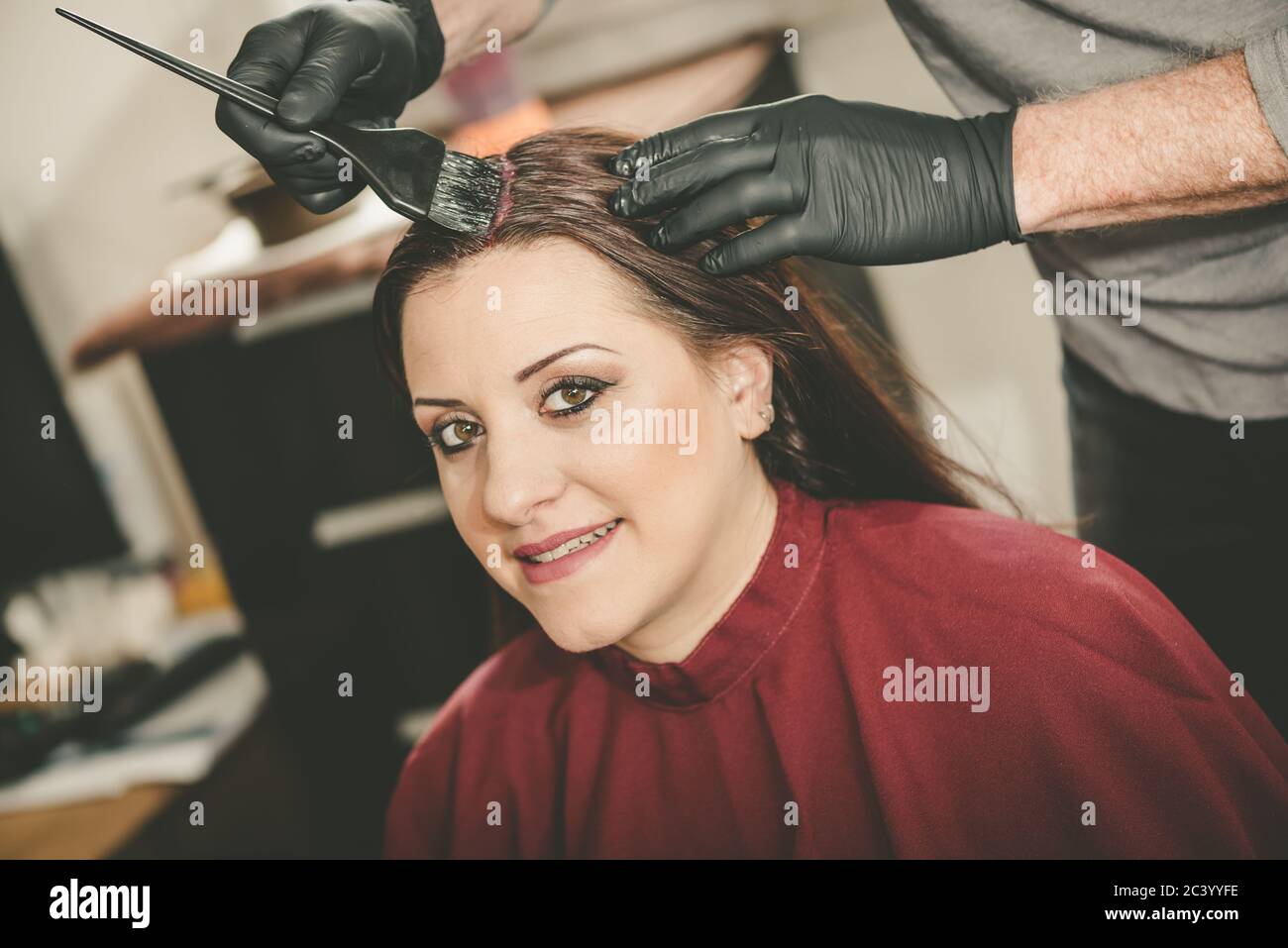 Hairdresser coloring female client hair Stock Photo - Alamy