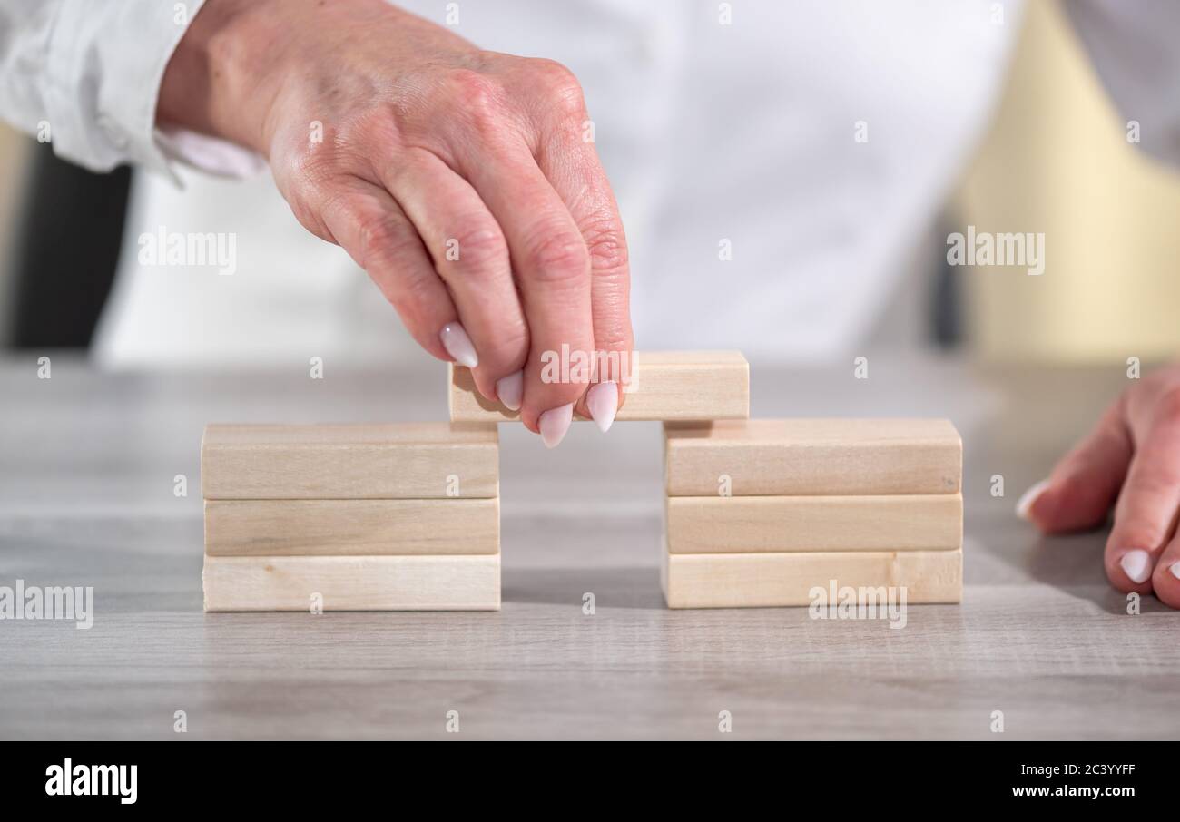 Female hand building a bridge with wooden blocks; concept of ...