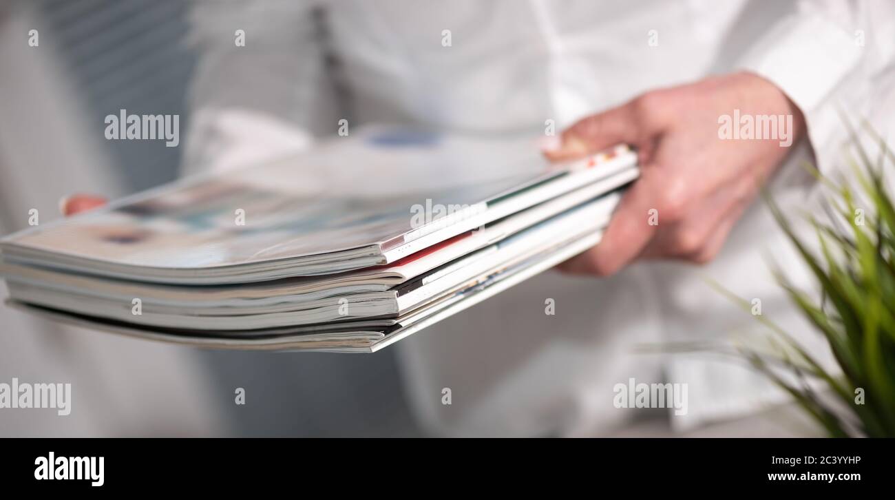 Female hands holding a stack of magazines Stock Photo - Alamy