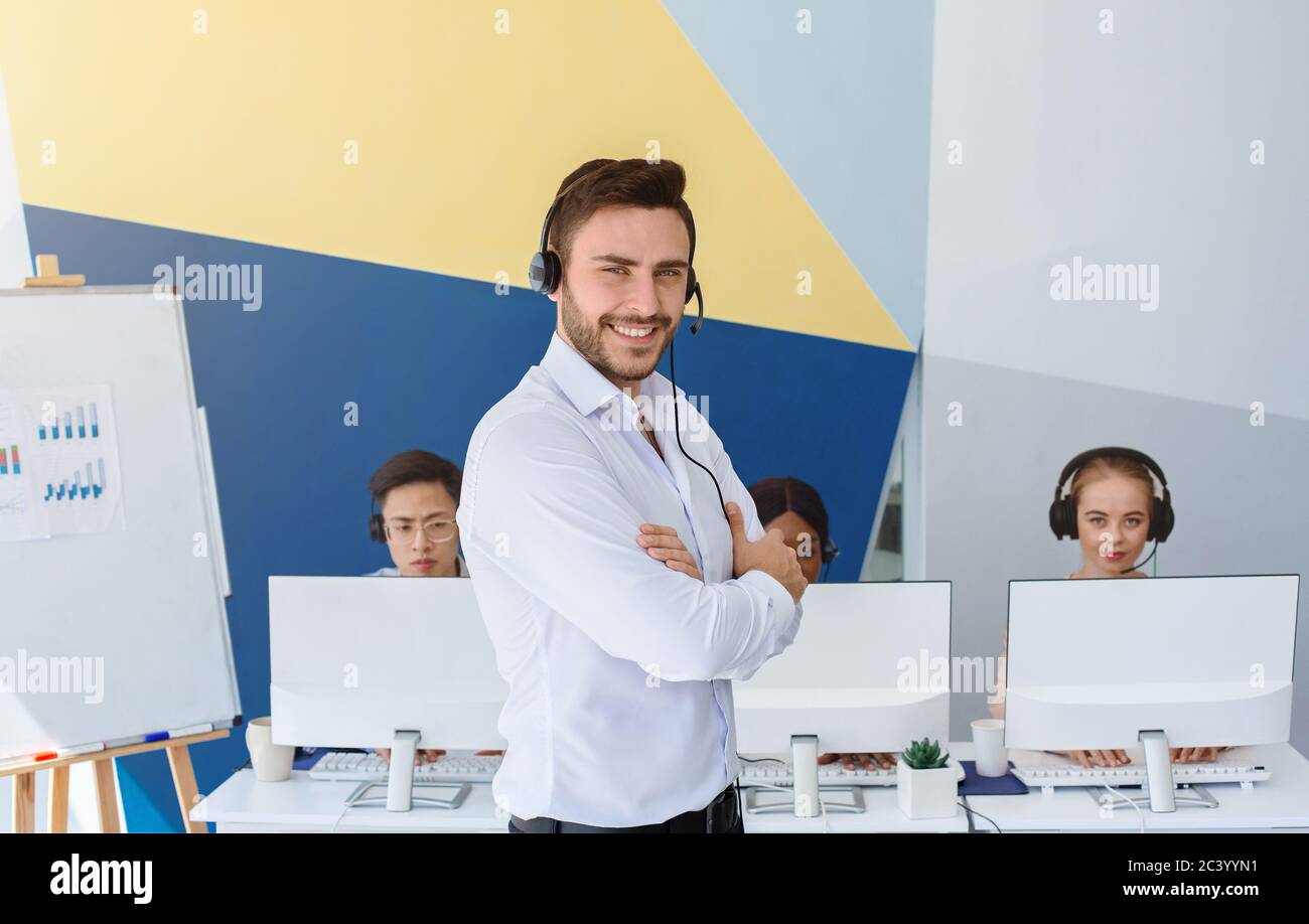 Happy male customer support executive and his colleagues at call centre ...