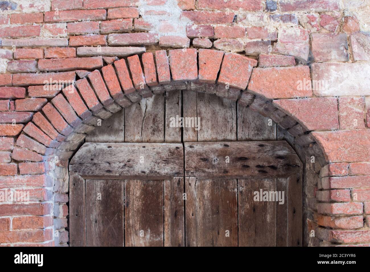 Detail of a brick arch with inside an old doorway Stock Photo - Alamy