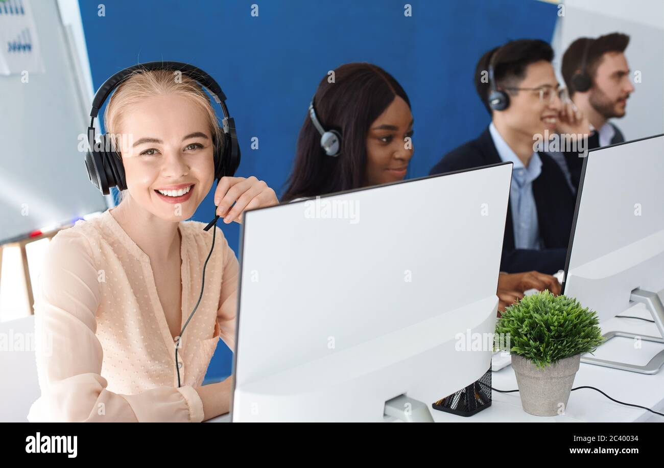 Joyful customer service agents with headphones communicating with ...