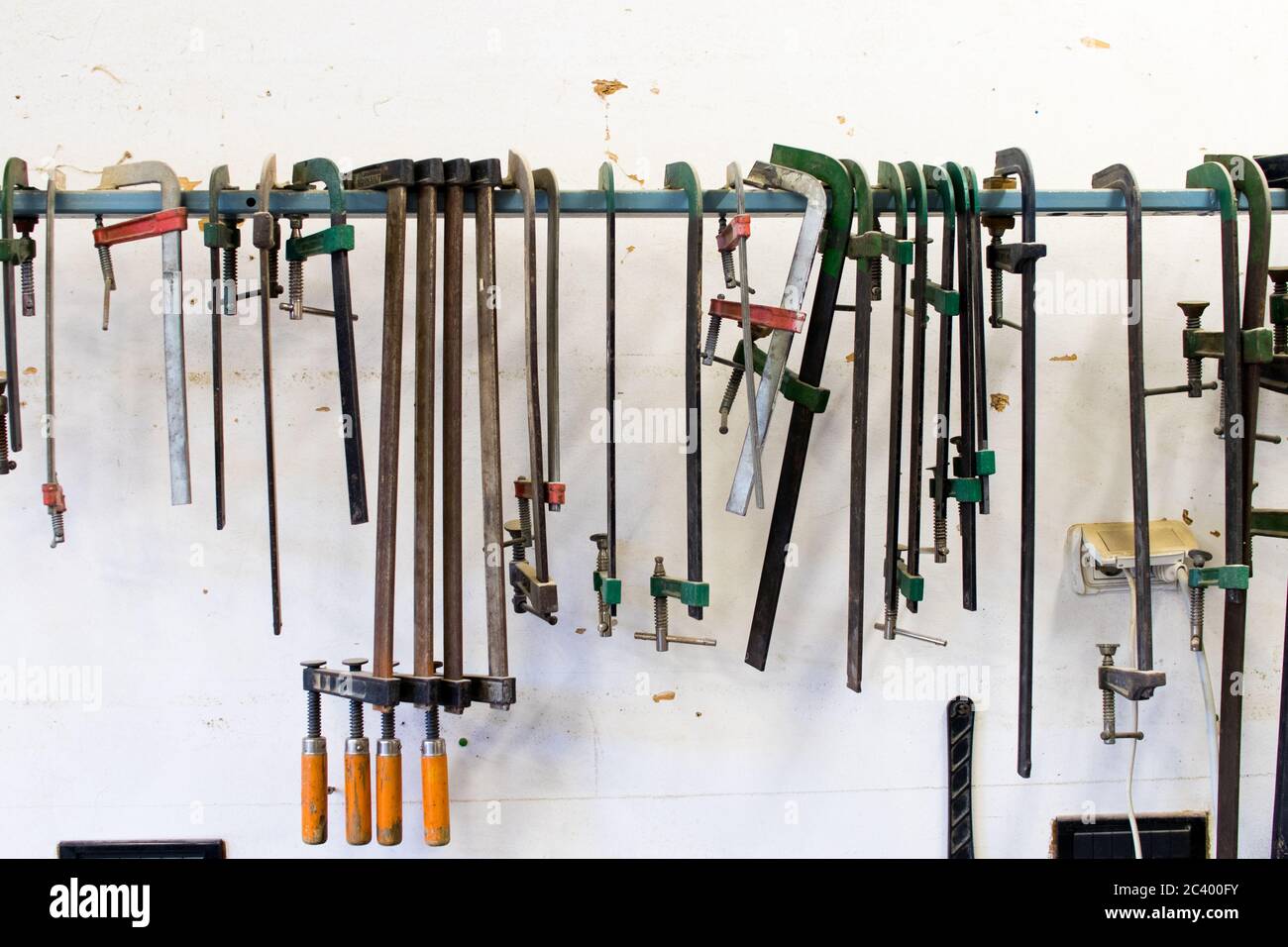 series of carpenter tools hung in the workshop. Clamps of various sizes ...
