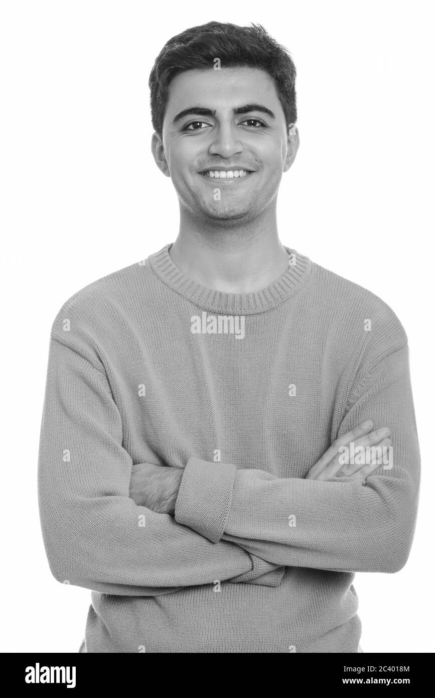 Portrait of happy young handsome Persian man smiling with arms crossed ...