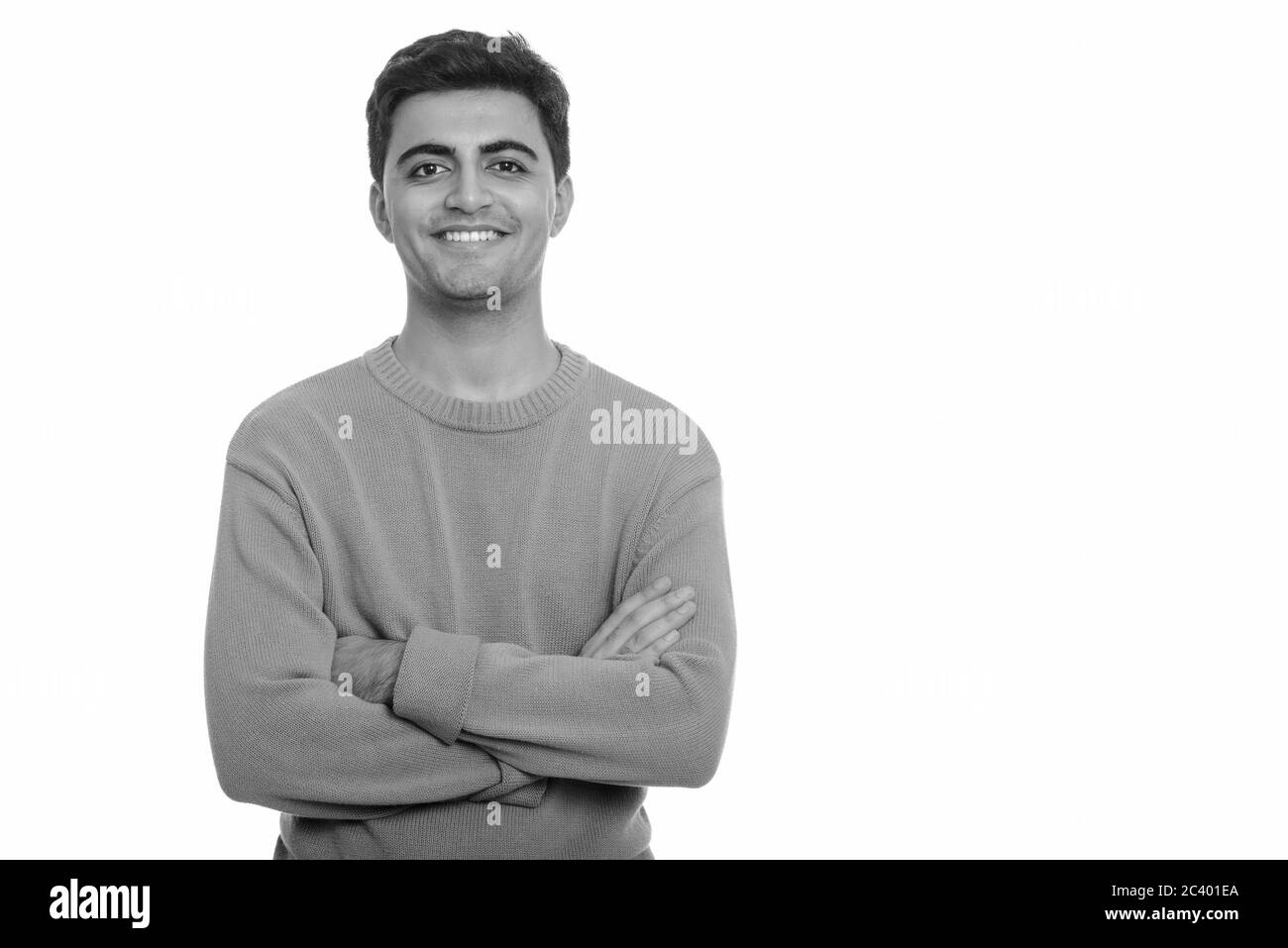 Portrait of happy young handsome Persian man smiling with arms crossed ...
