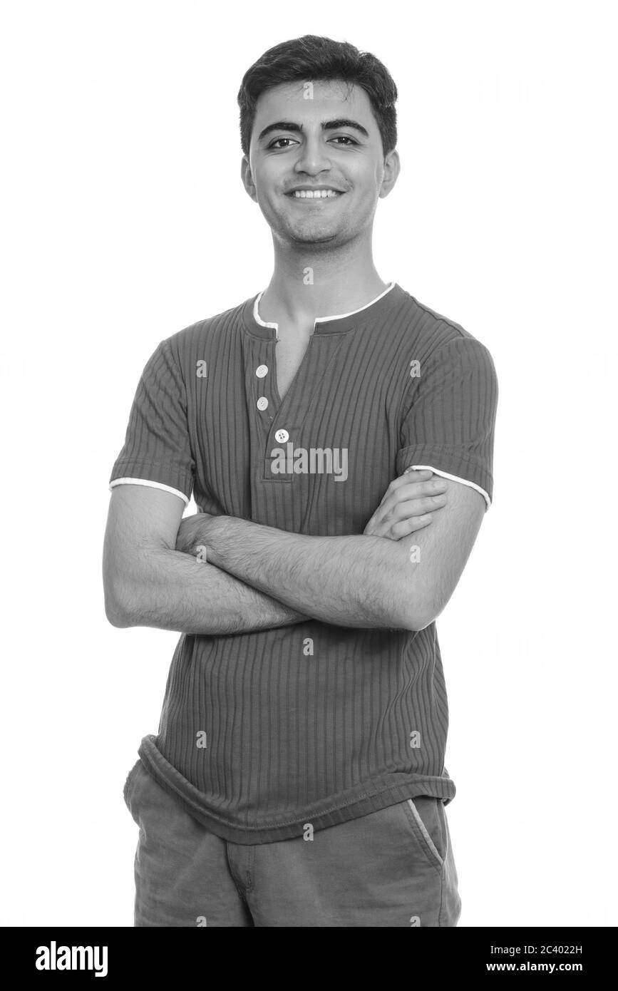 Portrait of happy young handsome Persian man smiling with arms crossed ...