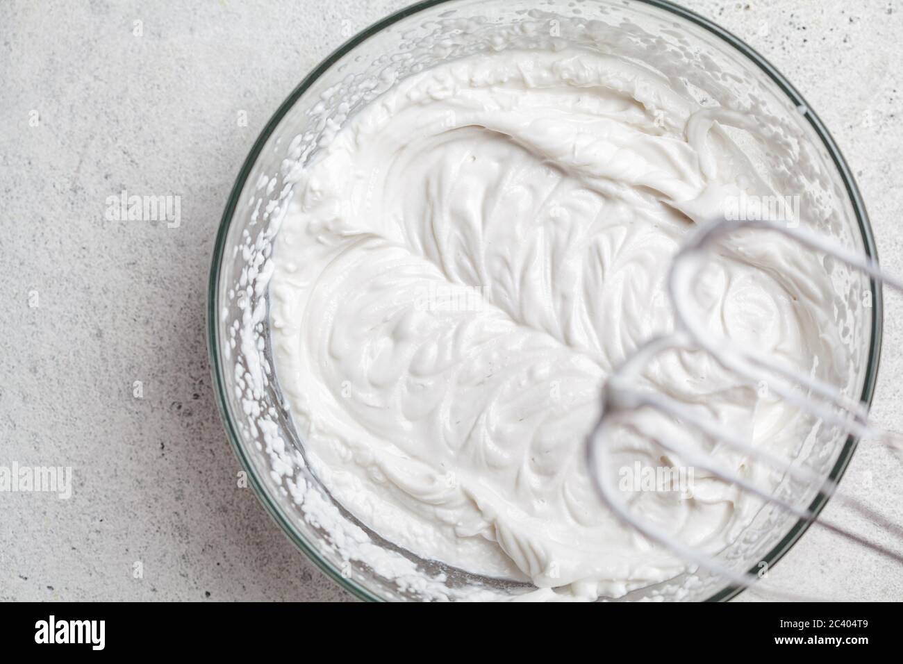 Cooking cream for cake in a glass bowl and mixer. Whipped white cream ...