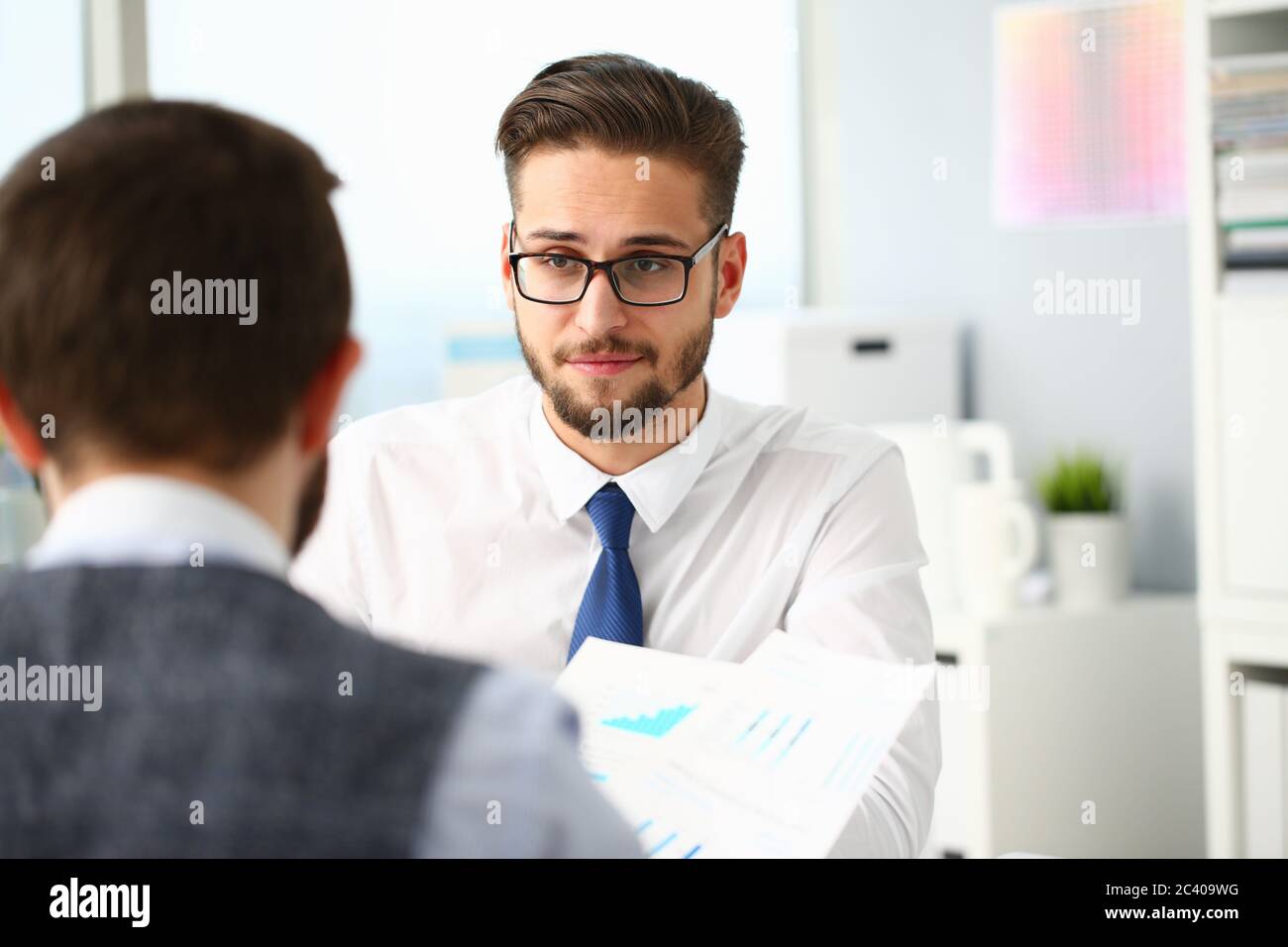 Handsome young man working with colleague in office Stock Photo - Alamy