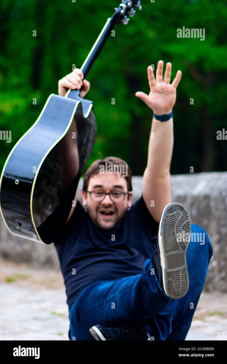 Young man falling down with guitar in his hands Stock Photo - Alamy