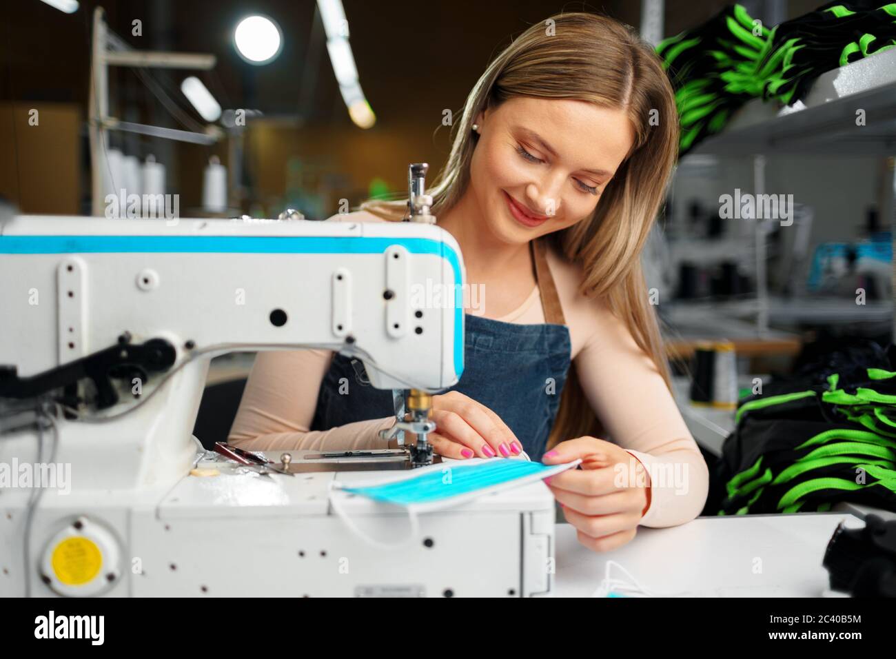 Seamstress woman at her workplace sewing clothes on sewing machine ...
