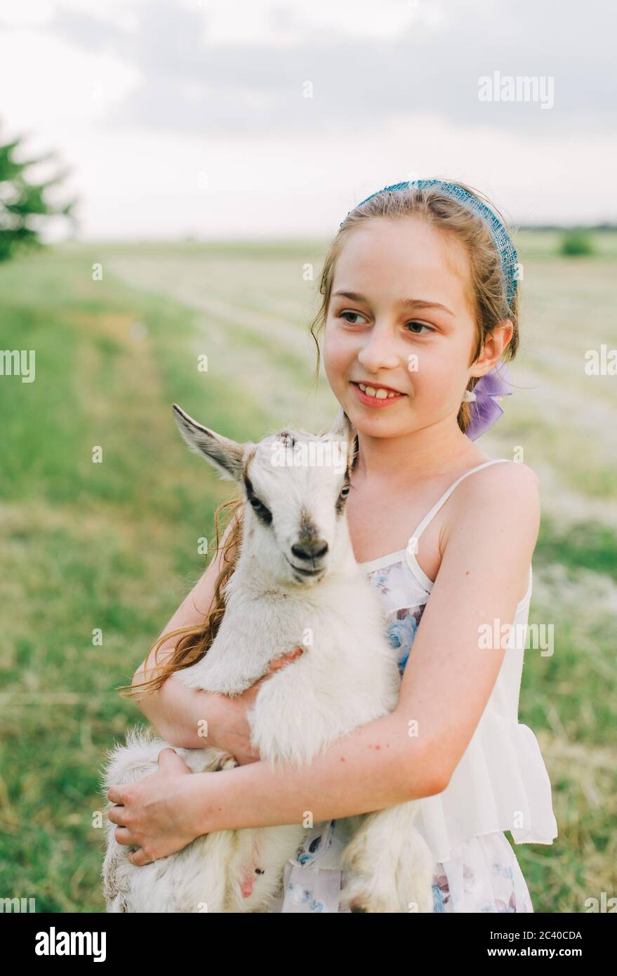 girl with baby goat on farm outdoors. Love and care. Village animals ...