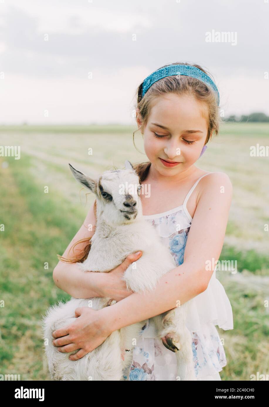 girl with baby goat on farm outdoors. Love and care. Village animals ...