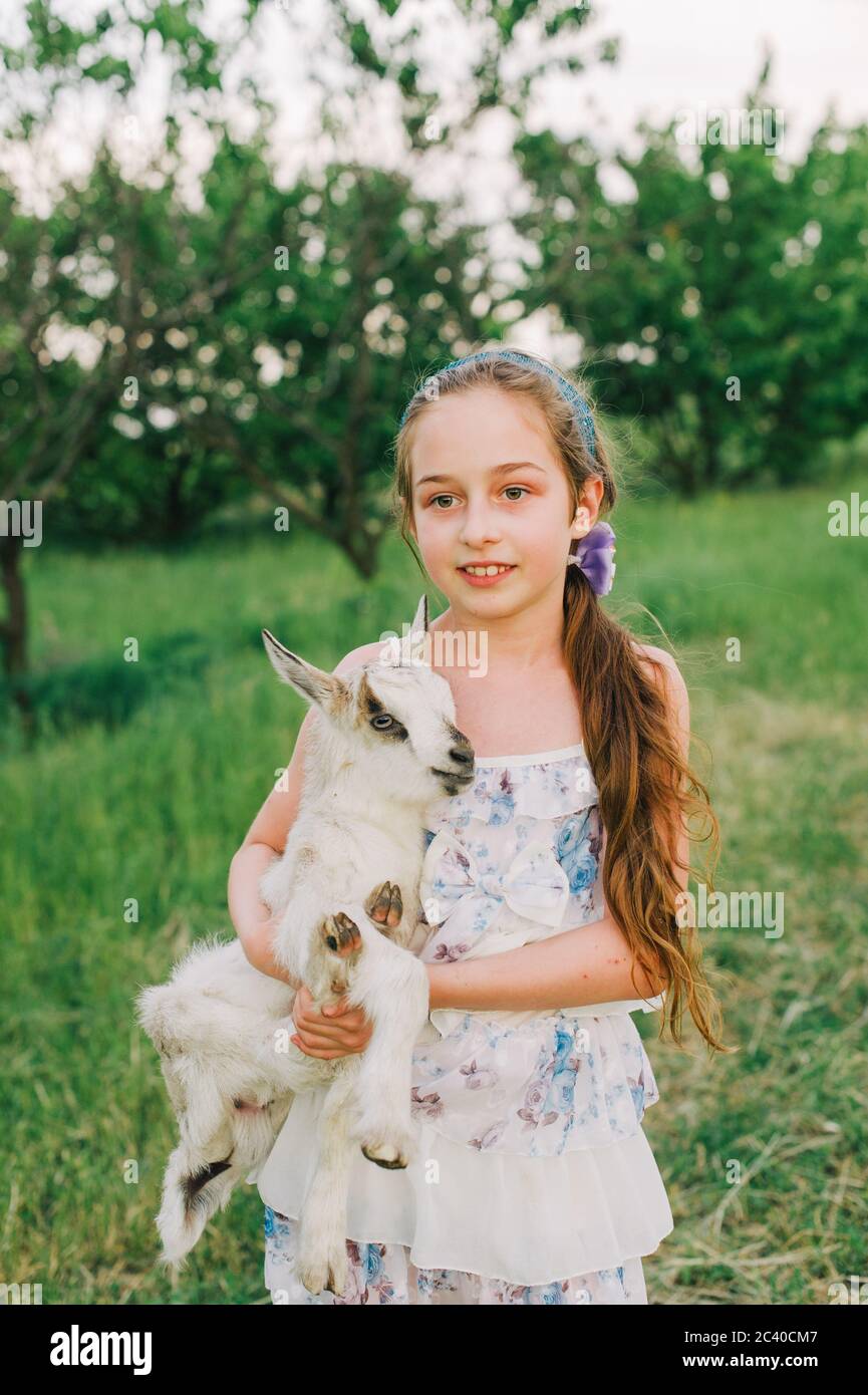girl with baby goat on farm outdoors. Love and care. Village animals ...