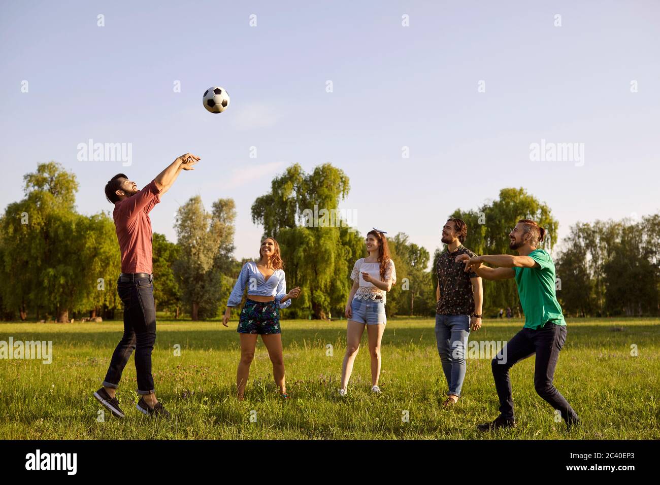Happy friends playing volleyball game in countryside on summer day ...