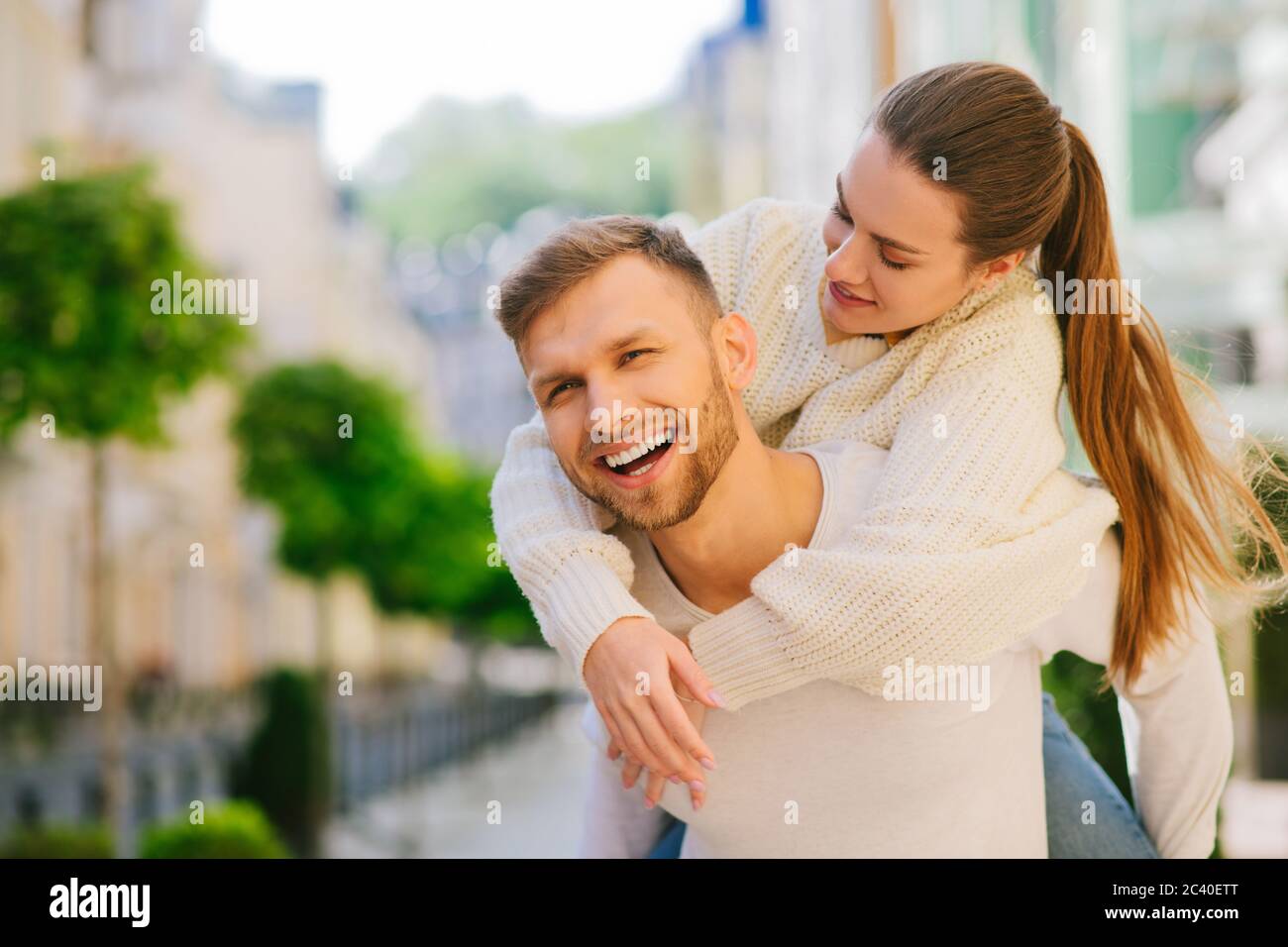 Young woman behind mans back hugging behind his neck Stock Photo - Alamy