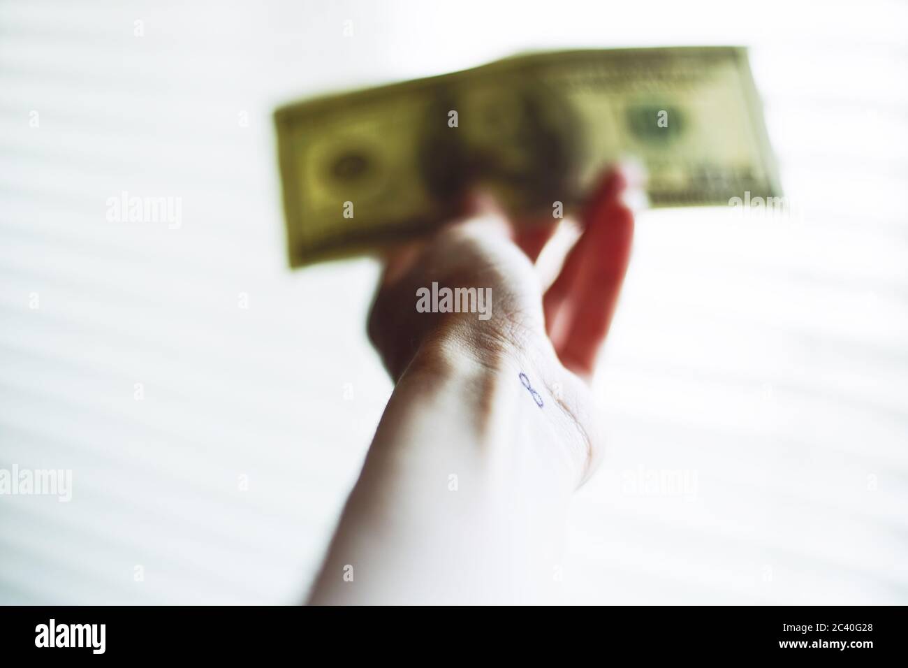 Tattoo infinity on the wrist. Blurred dollar bill in hand on a white ...