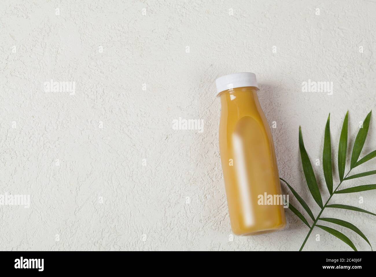 yellow mango smoothie on white background, served in bottle with palm ...