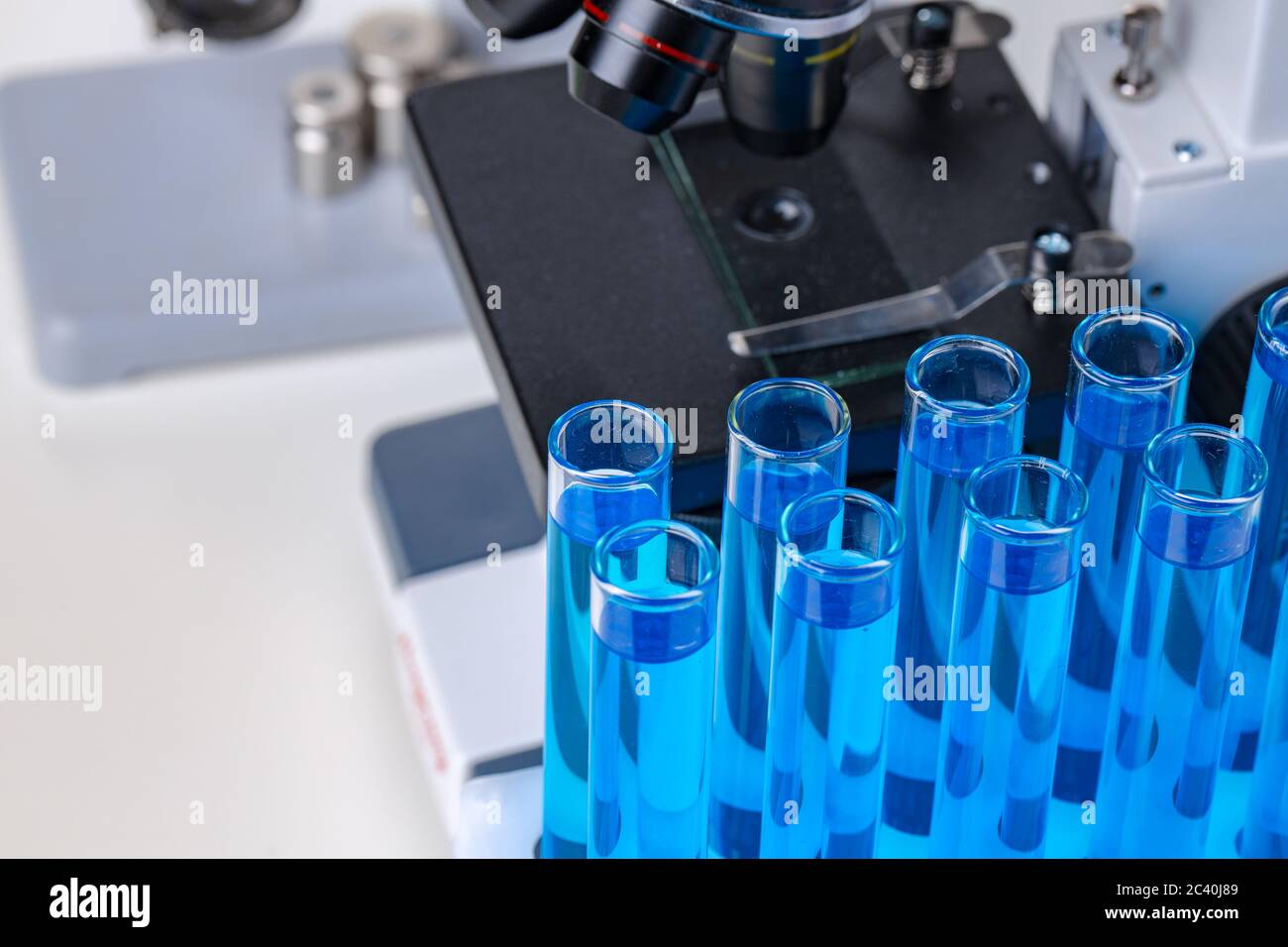 Close up of laboratory microscope with set of test tubes with blue ...