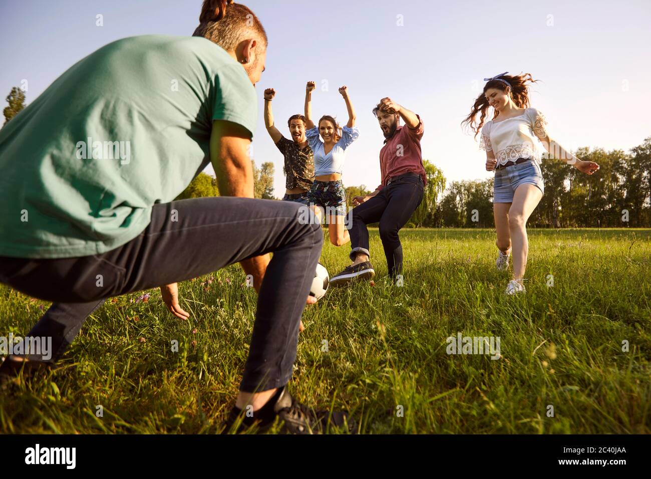 Happy friends playing soccer on green meadow. Group of college students ...